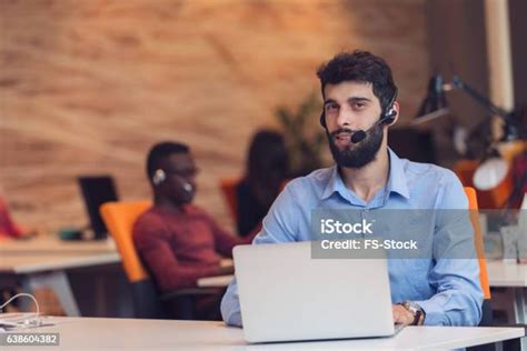 사무실에서 노트북에서 일 하는 헤드폰을 착용 하는 사업 노트북 사용하기에 대한 스톡 사진 및 기타 이미지 노트북 사용하기 모던 양식 바쁜 Istock