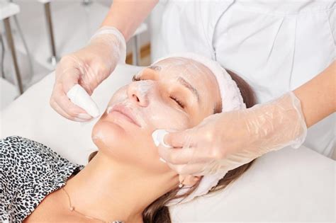 Premium Photo Beautician Removing Facial Cream Mask From Woman Face Skin With Cosmetic Wipes