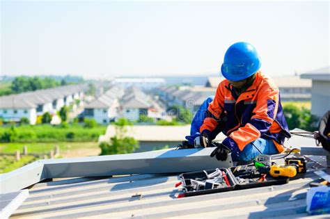 male technician worker installing solar panels on rooftop of industrial