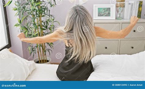Mature Woman With Grey Hair Stretching In Bright Bedroom Indicating