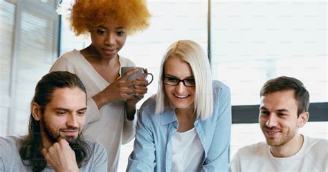 카페에서 함께 일하고 컴퓨터를 사용하고 커피를 마시고 아이디어를 공유하는 친구들 아름다운 웃는 여자들과 잘생긴 남자들이