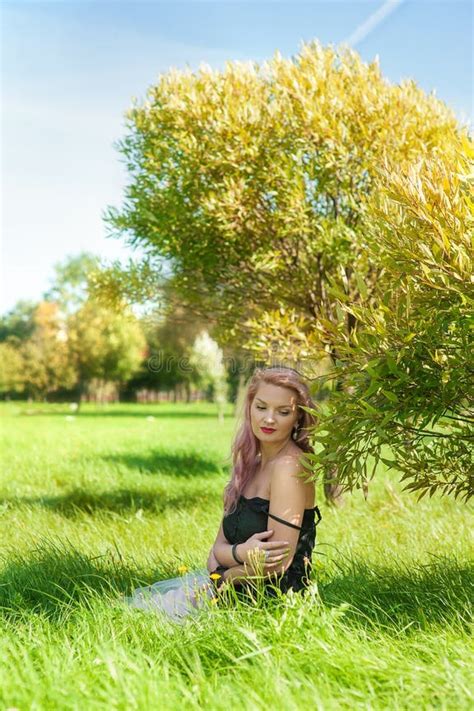 Beautiful Woman Sitting On The Grass Near The Tree Outdoor Stock Image