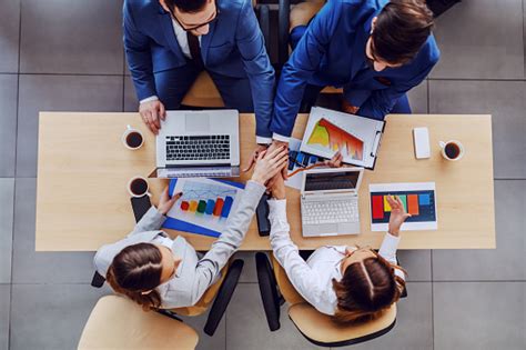 테이블에 앉아 손을 쌓아 네 성공적인 비즈니스 사람들의 상단보기 표에는 주식 시장에 대한 차트와 통계가 있습니다 경영자에 대한 스톡 사진 및 기타 이미지 Istock