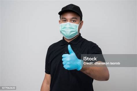 보호 마스크와 의료 용 고무 장갑을 착용한 검은 배달 아시아 남자는 고립 된 흰색 배경에 엄지 손가락으로 서 있습니다 안전 제공 개념 엄지손가락을 위로에 대한 스톡 사진 및