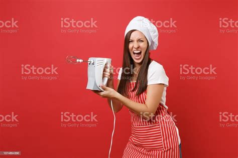 주부 여성 요리사 요리사 또는 줄무늬 앞치마 흰색 T셔츠 모자 요리사 모자 빨간 벽 배경에 고립 된 베이커 여자는 부엌 믹서를 개최 크리스마스 생강 비스킷 요리 복사 공간