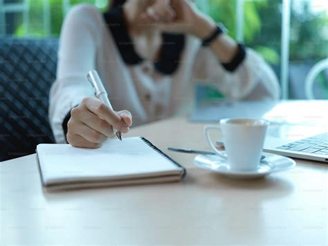 회의실의 나무 테이블에 있는 빈 노트에 메모를 하는 여성 회사원의 모습을 닫습니다 사진 Unsplash의 앉아 이미지