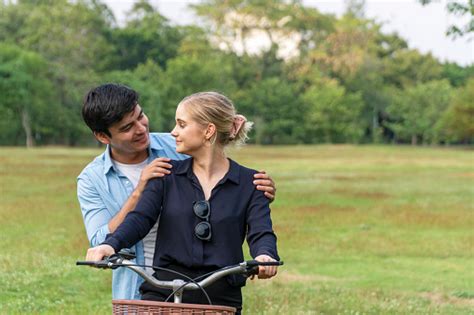 라이프 스타일 로맨틱 한 연인 개념 자전거를 밀고 있는 활동적인 젊은 부부는 함께 휴가를 보내며 팩에 담긴 이야기를 나누며 휴식을 취합니다 잘 생긴 남자 와 여자 친구 레저