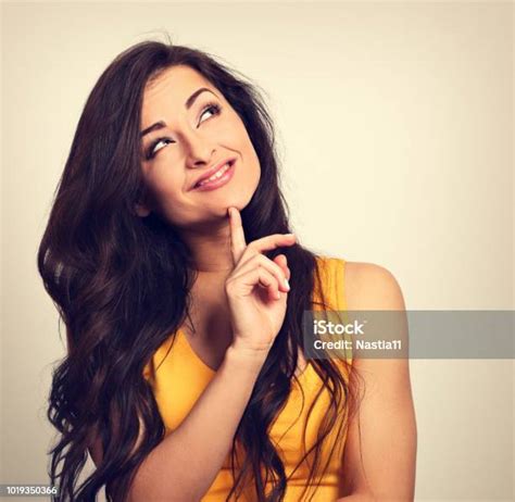 아름 다운 흥분된 젊은 웃는 여자 생각 하 고 노란색 셔츠에 긴 머리를 올려 얼굴 아래 손가락으로 근접 촬영 톤의 빈티지 초상화 갈색 머리에 대한 스톡 사진 및 기타 이미지
