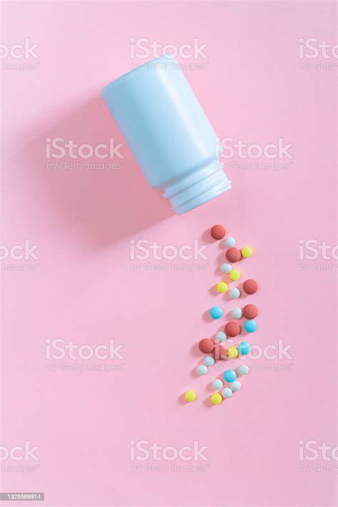 분홍색 배경에 알약과 알약 병 흰색과 오렌지 색상의 둥근 알약은 흰색 플라스틱 알약 병의 분홍색 배경에 쏟아져 맨 위 보기입니다 약용 약품 바이오 해킹 개념 트렌디 한