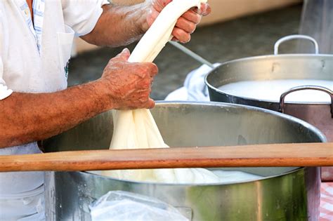 남자는 치즈 유제품에 큰 금속 통으로 모짜렐라 디 부팔라를 요리합니다 인간의 손이 치즈를 만들기 위해 신선한 반죽을 모읍니다
