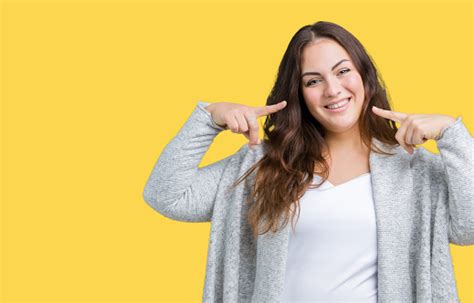 플러스 크기 젊은 여 자가 아름 다운 배경 웃 고 자신감 보여주는 손가락 치아와 입 지적 고립 동안 겨울 자 켓을 입고 건강