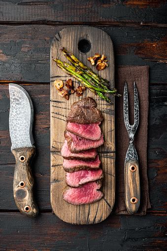 육즙 이 많은 스테이크 중간 희귀 쇠고기 Filet Mignon 또는 아이 필레 양파와 아스파라거스 나무 서빙 보드에 고기 칼과