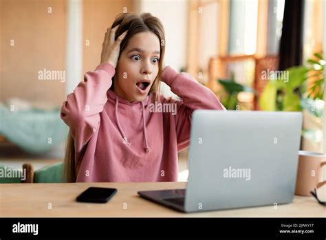 Shocked Teenage Girl Looking At Laptop And Touching Head Having
