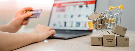 온라인 쇼핑 상자 또는 소포는 테이블과 장바구니에 놓입니다 흐릿한 배경 여자는 신용 카드를 사용하여 노트북에서 온라인 구매를 합니다 온라인 서비스 뉴 노멀 쇼핑 배송 가격에