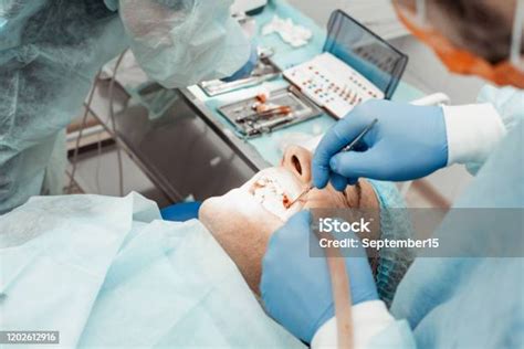 치과 의사는 수술 임플란트 배치를 수행합니다 실제 작동 치아 추출 임플란트 전문 유니폼 과 치과 의사의 장비 의사의 직장을 갖추는 의료 서비스 치과 거울에 대한 스톡 사진