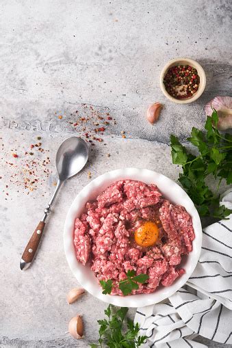 생 다진 고기 밝은 회색 콘크리트 배경에 흰 접시에 고기 쇠고기 돼지 고기 또는 양고기 향신료 허브 및 달걀을 갈아 넣습니다 요리를위한 신선한 다진 고기 음식 요리 배경