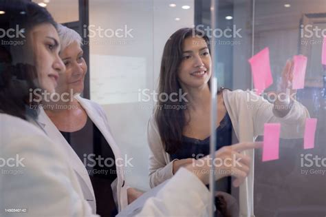 팀 비즈니스 사람들의 그룹은 스티커 메모로 계획을 세우기 위해 브레인 스토밍하고 회의를 하거나 사무실에서의 마케팅 아이디어 및 영감 팀워크 개념에 대한 유리에 게시합니다