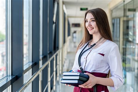 특별한 유니폼을 입은 젊은 여성 치과 의사가 복도에 서서 이상적인 이빨로 미소 짓고 있습니다 20 29세에 대한 스톡 사진 및 기타 이미지 Istock