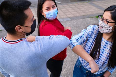 코로나 바이러스 확산을 방지하기위한 팔꿈치 범프와 새로운 사회적 불변 인사를하고 얼굴 마스크를 착용 젊은 친구 20 24세에