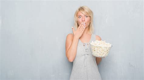 그런 지 회색 벽 팝 옥수수 커버 입을 손으로 실수 두려움 침묵 비밀 개념에에서 무서 워의 표현에 대 한 수치와 충격을 먹는 동안 성인 백인 여자 가리기에 대한 스톡 사진