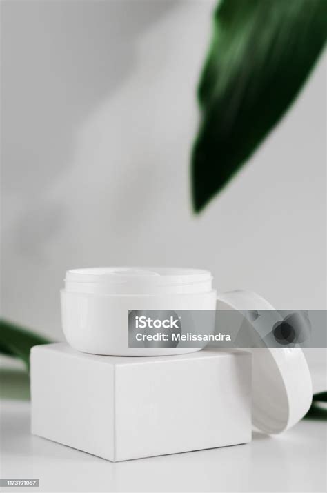 천연 화장품 크림 항아리와 녹지 측면보기 흰색 플라스틱 용기를 열고 배경에 흐린 식물 잎 유기 화장품 창조적 인 개념 스킨 케어위생 소품 개념에 대한 스톡 사진 및 기타