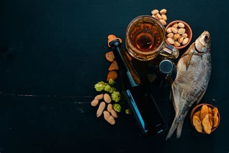 맥주와 스낵 소금에 절인된 크래커 말린 물고기 칩 견과류 땅콩 피스타치오 에 검은 나무 배경 텍스트에 대 한 여유 공간입니다