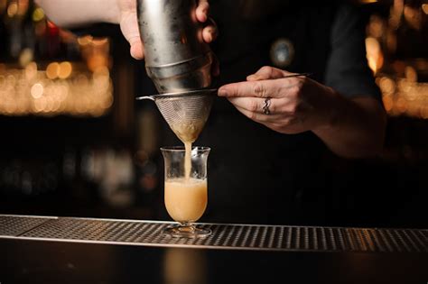남성 바텐더는 체를 통해 스틸 셰이 커에서 맛 있는 칵테일을 붓는 각얼음에 대한 스톡 사진 및 기타 이미지 각얼음 갈색