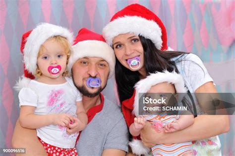 크리스마스 가족 가까이 그들의 입에 젖꼭지와 초상화 신생아 아가와 그들이 입고 산타 클로스 모자 팔에 2 년 딸과 함께 아빠 엄마 12월에 대한 스톡 사진 및 기타 이미지