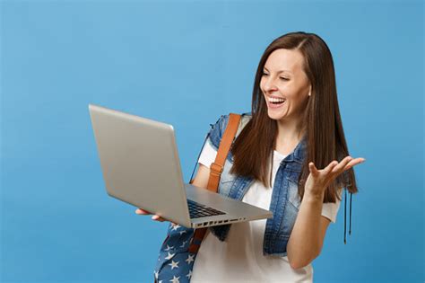 젊은 웃는 여자 학생 배낭 데님 옷에 파란색 배경에 고립 손을 확산 노트북 Pc 컴퓨터에 작업을 사용 하 여 개최 대학에서 교육입니다 광고에 대 한 공간을 복사 합니다