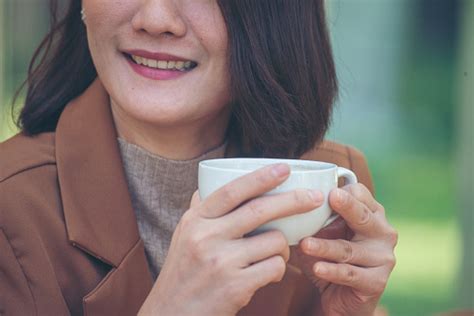 클로즈업 사업가의 손은 뜨거운 커피를 마시는 것을 좋아합니다 녹색 정원 카페에서 검은 커피 컵을 들고있는 여성의 손 커피 숍에서 블랙 커피 또는 핫 초콜릿을 가진 비즈니스