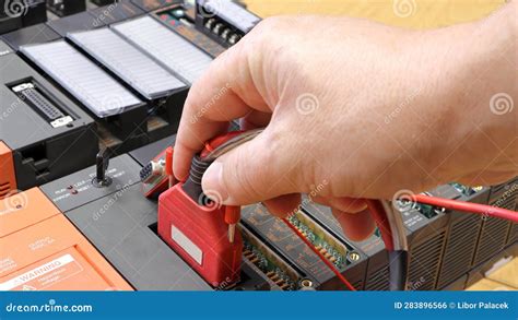 The Electrical Engineer Connects The Communication Cable To The PLC Automaton Stock Photo
