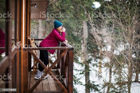 겨울 숲의 오두막 발코니에 서있는 차 한 잔을 든 젊은 성인 여성 35 39세에 대한 스톡 사진 및 기타 이미지 35 39세 건강한 생활방식 겨울 Istock