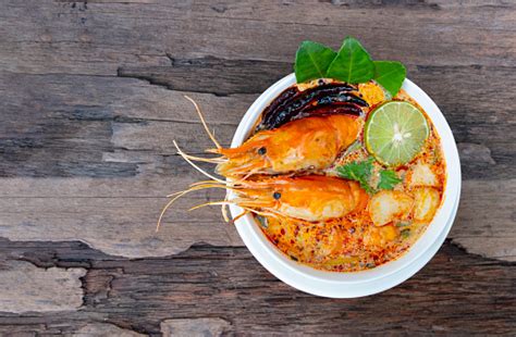 Tom Yum Goong 또는 새우 수프 매운 신 수프 태국 전통 음식은 칠리 라임 레몬 그라스 라임 잎 상단에서 오래된 나무 배경에 흰색 접시에 밥을 포함합니다 건강한