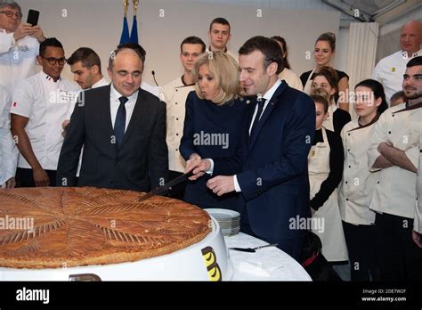 French President Emmanuel Macron And His Wife Brigitte Slice A Traditional Epiphany Cake During