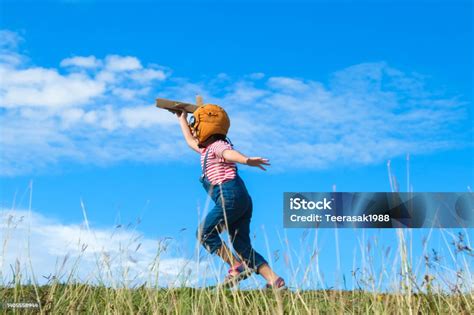 화창한 날에 장난감 비행기를 손에 들고 초원을 뛰어 다니는 귀여운 소녀 푸른 여름 하늘 배경에 골판지 비행기로 노는 행복한 아이 어린 시절의 꿈 상상력 개념 손에 대한 스톡