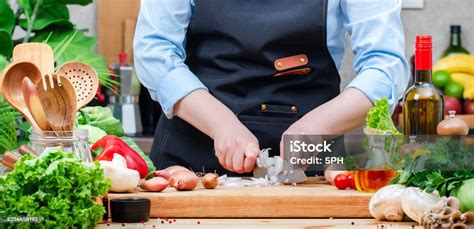 가정 요리사는 나무 테이블 주방 용품 야채 허브 및 요리 재료가 있는 아늑한 주방에서 칼로 샬롯 양파를 자릅니다 건강한 비건 음식 요리 조리법 음식 블로깅 가정 생활에 대한