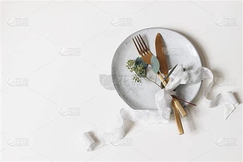 节日的餐桌布置金色餐具浆果桉树枝瓷盘和丝带孤立在白色的桌子背景地中海婚礼或餐厅菜单概念平躺