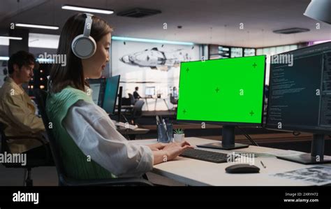 Female Asian Game Programmer Coding On Desktop Computer With Green