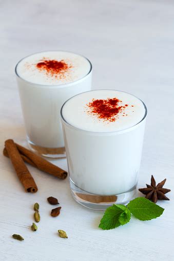 라시 음료는 고추와 흰색 배경에 신선한 녹색 민트와 함께 음료 향신료가 함유된 차가운 유제품 계피와 스타 아니스 인도 요리 복사 공간을 복사합니다 디저트 테이블에 프로