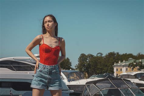 빨간 스파게티 스트랩 탑과 파란색 데님 반바지를 입은 여자가 낮 동안 부두에 서 있다 사진 Unsplash의 무료 상트페테르부르크 이미지
