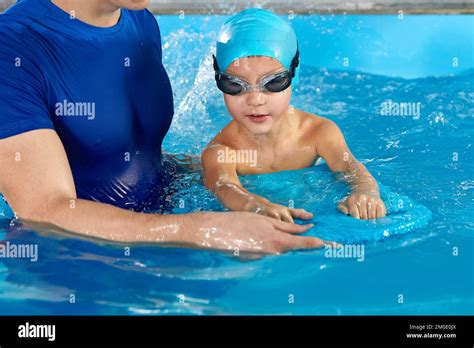 Male Trainer Teaching Preschool Boy How To Swim In Indoor Pool With