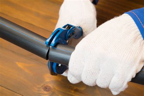 어두운 나무 배경에 노동자u2019s 흰색 장갑에 손을 파란색 가위로 검은 폴리 프로필렌 파이프를 잘라 가위에 대한 스톡 사진 및 기타 이미지 Istock