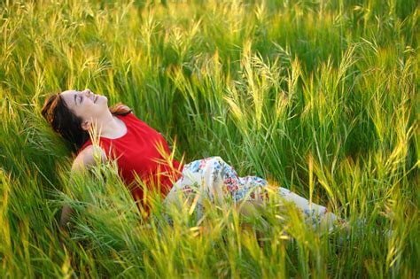 아름다운 젊은 여자 빨간 드레스에 녹색 초원의 필드에 누워 야외 자연을 즐기는 녹색 봄 작물에 미소 20 29세에 대한 스톡