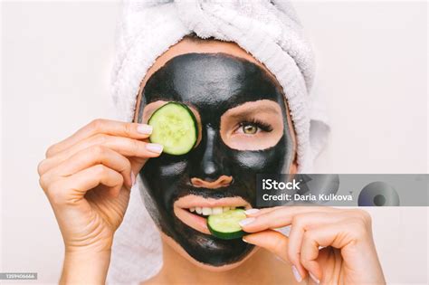 아름다운 여자는 오이 슬라이스와 검은 정화 숯 얼굴 마스크를 적용합니다 페이스 스킨 케어 건강관리와 의술에 대한 스톡 사진 및 기타 이미지 건강관리와 의술 건강한 생활