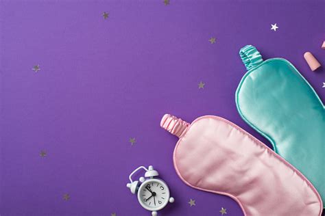 작은 흰색 시계와 두 개의 실크 눈가리개 핑크와 밝은 파란색 의 상단 보기 사진은 별 모양의 산란 색종이와 보라색 고립 된 배경 카피 스페이스에 두 개의 귀마개를 가지고