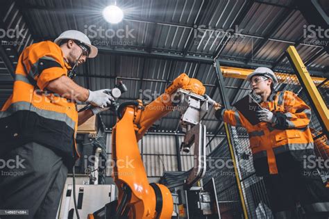 자동화 공장에서 일하는 엔지니어 팀 서비스 로봇 용접 안전복을 입은 사람들은 로봇 팔 소프트웨어 프로그래밍 또는 자동화 제조