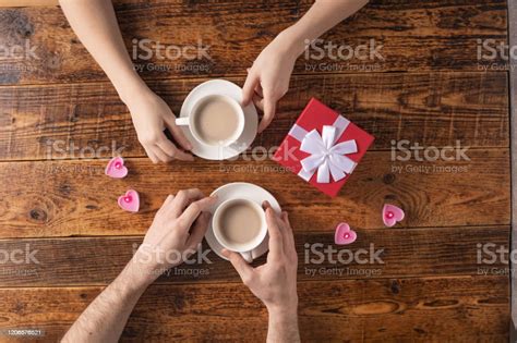 발렌타인 데이 축하 개념입니다 사랑하는 사람을위한 좋은 선물 나무 테이블 배경에 커피 잔과 남자와 여자의 손 공간을 복사합니다