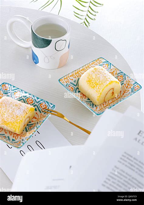 A Vertical Shot Of Aesthetic Table Setup With Swiss Roll Dessert And A Cup Of Tea Stock Photo