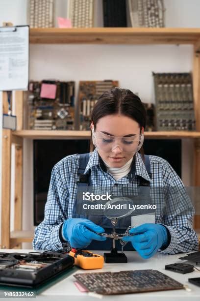 실험실에서 노트북 마더보드를 수리하는 기술자는 돋보기로 작은 세부 사항을 검사합니다 컴퓨터 하드웨어 전자 수리 업그레이드 및