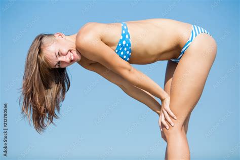 Girl In Blue Bikini Posing Bent Leaning On Her Knees And Winking Stock